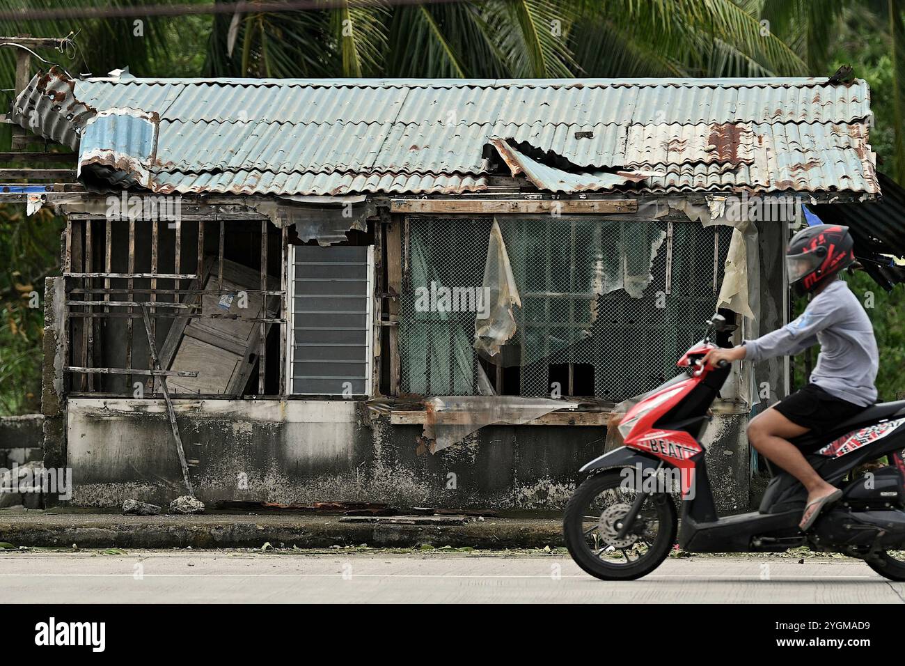A resident passes by a damaged house after Typhoon Yinxing, locally ...