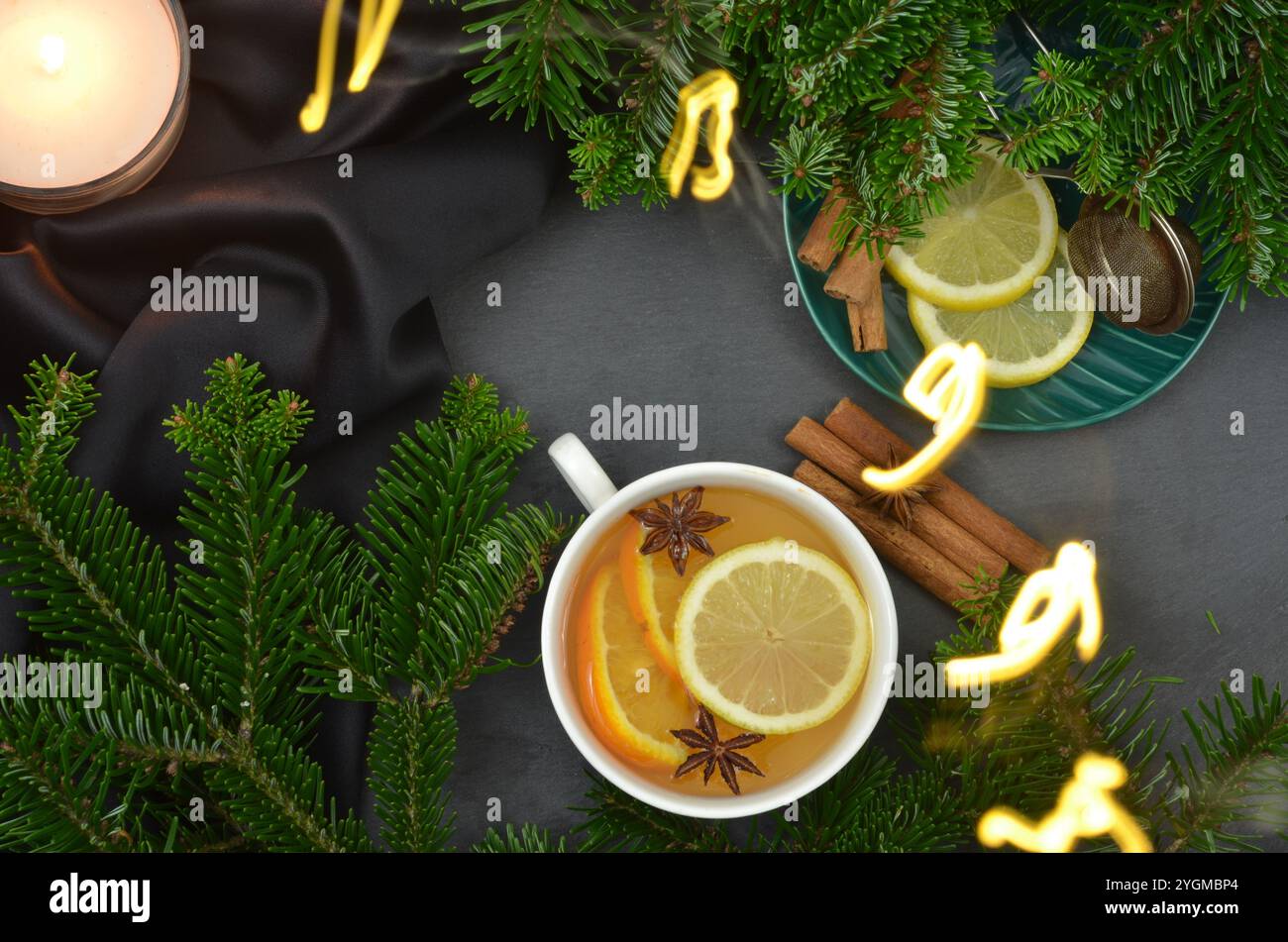 Burning candle and Christmas lights, cup with drink, lemon, anise stars ...