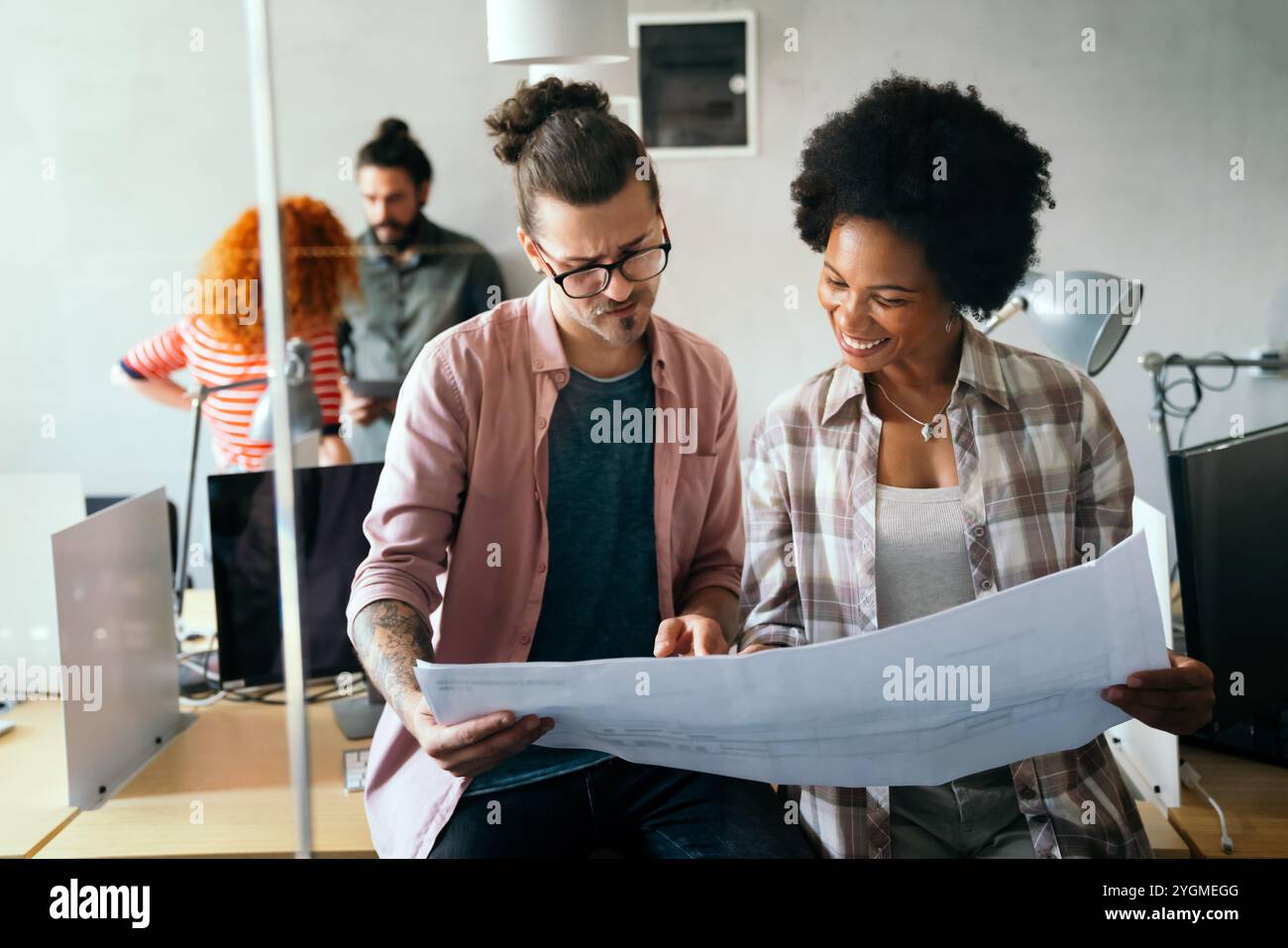 Engineers helping design work on blueprints, collaborate on structural ...