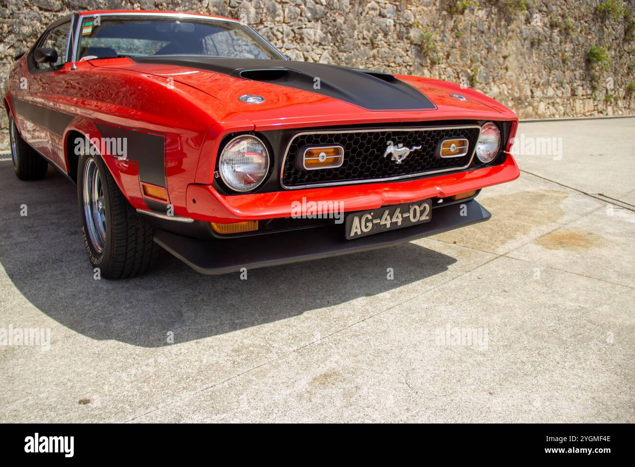 Classic red ford mustang mach 1 parked in front of a stone wall ...