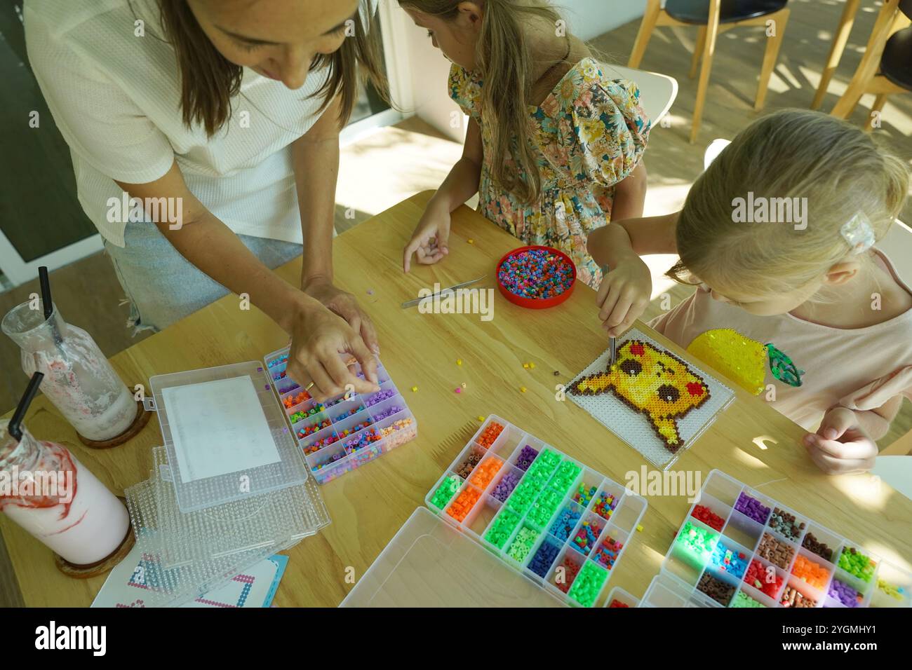 Teacher in workshop teched two girls how to assemble a thermo mosaic ...