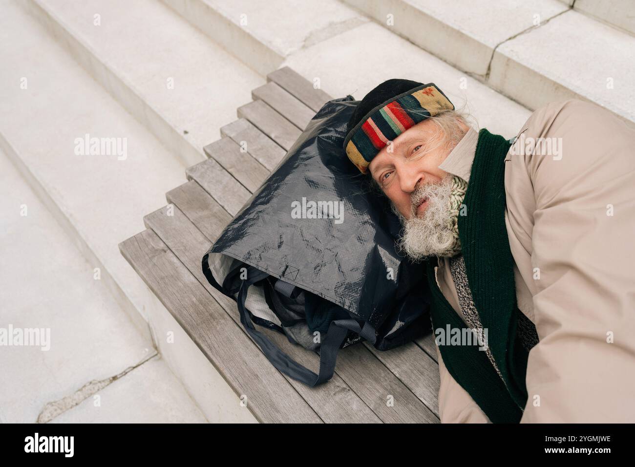 Top view of elderly homeless man sleeping on urban bench outside, using ...