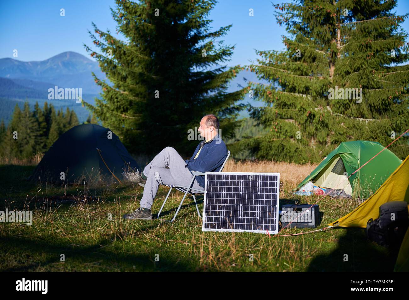 Man using photovoltaic solar panel for charging portable power station ...