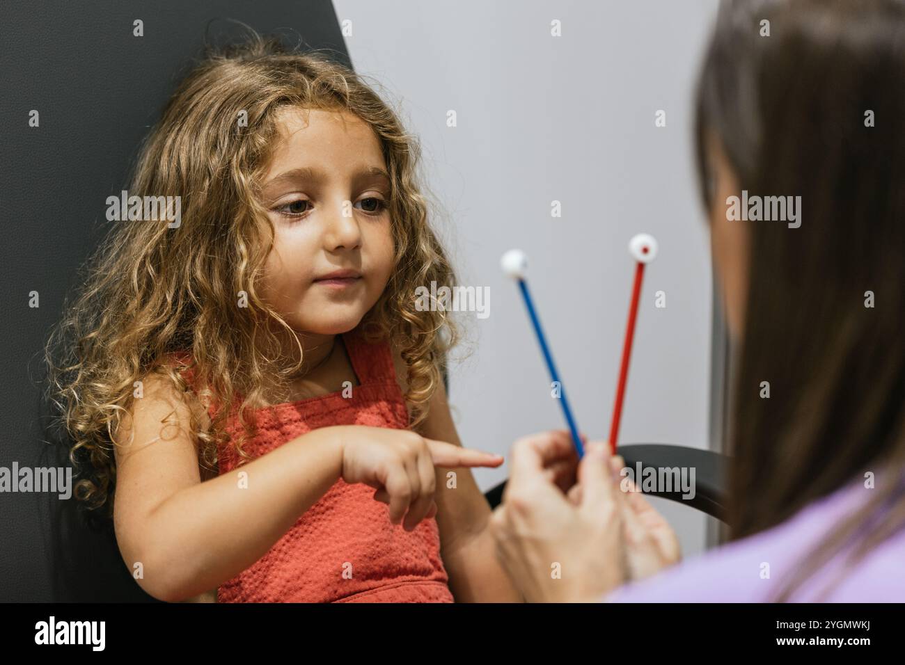 Little girl taking pediatric eye exam with optometrist using red and ...