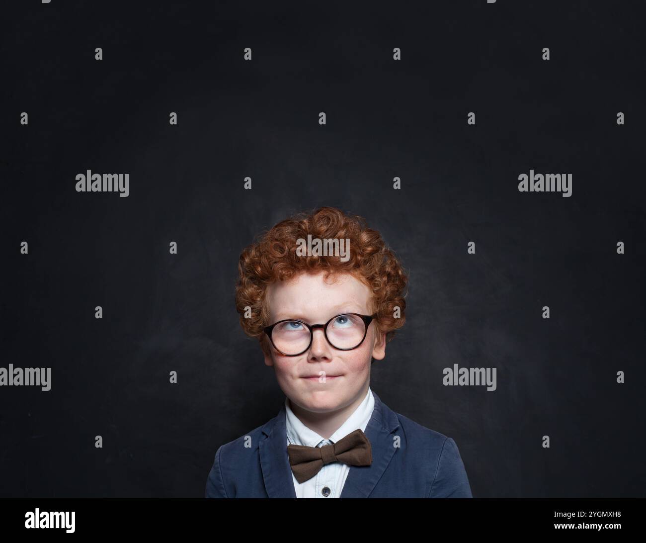 Smart child school boy in school uniform looking up on blackboard ...