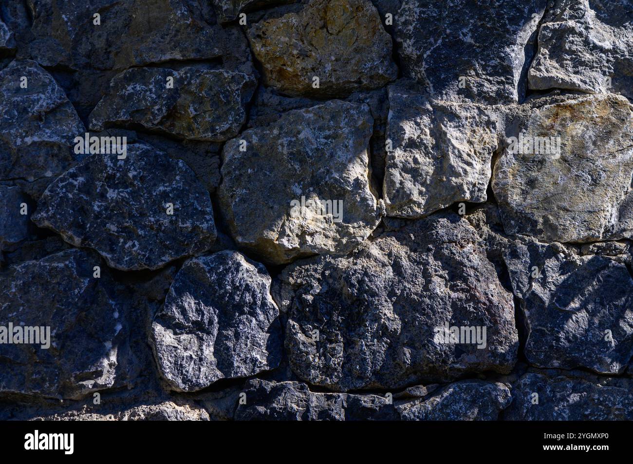 Rough stones create a captivating texture as sunlight plays across the ...