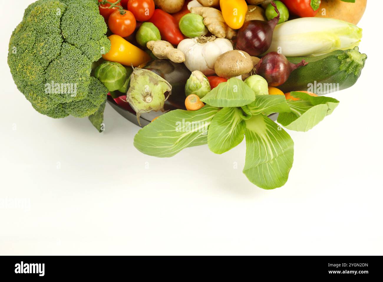 Raw mixed organic vegetables arranged at the top of the frame, on white ...