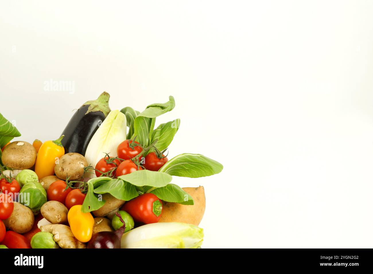 Raw mixed organic vegetables in the left corner of the frame, on white ...