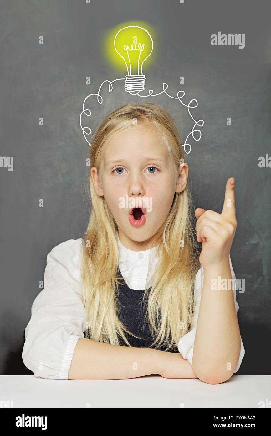 Funny child girl student with yellow light bulb on school blackboard ...