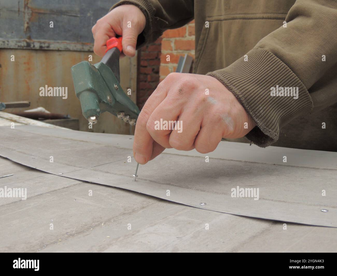 inserting a thin long aluminum rivet into a metal structure, the worker ...