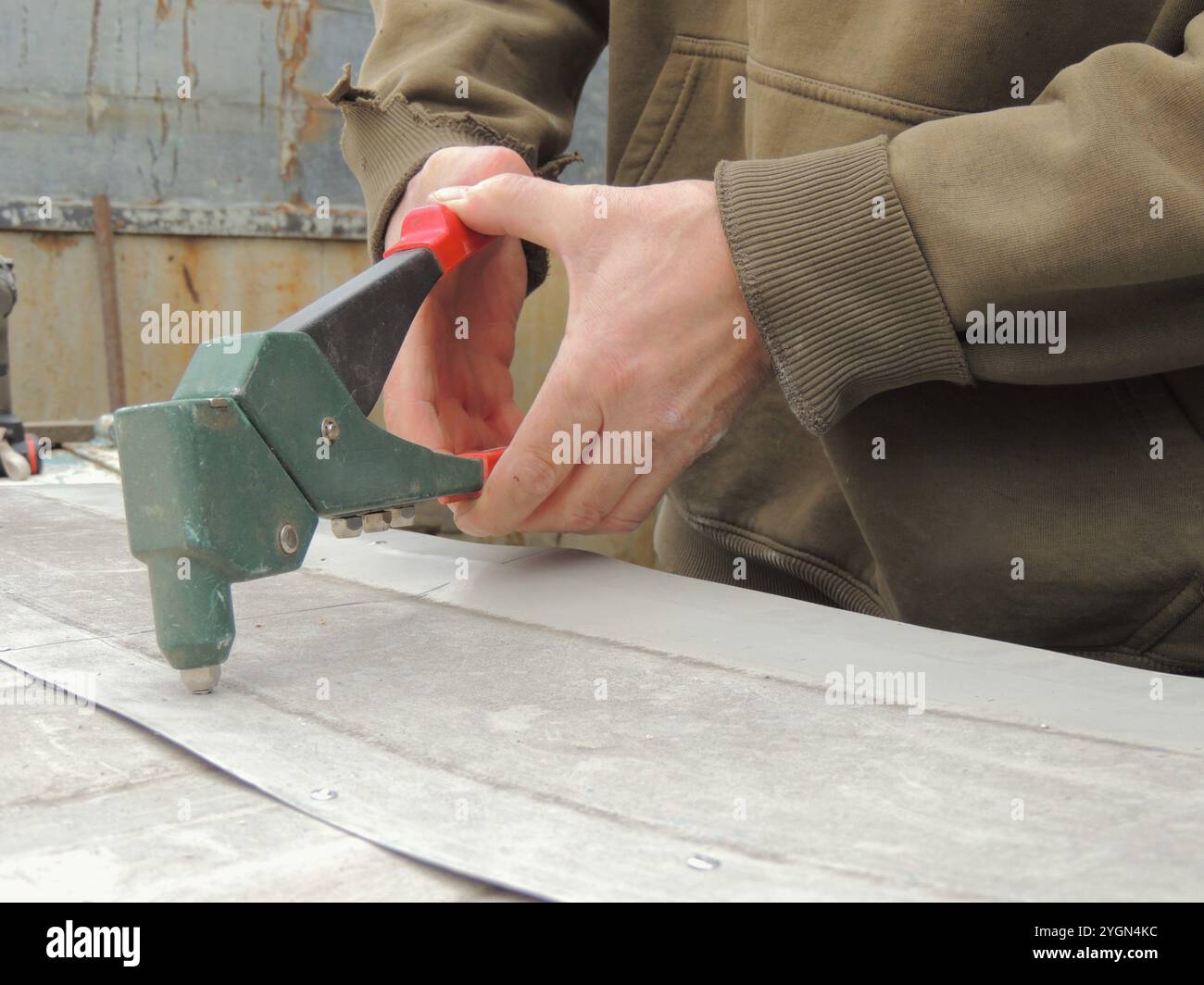 close-up of worker's hands with riveting gun during work, placing ...