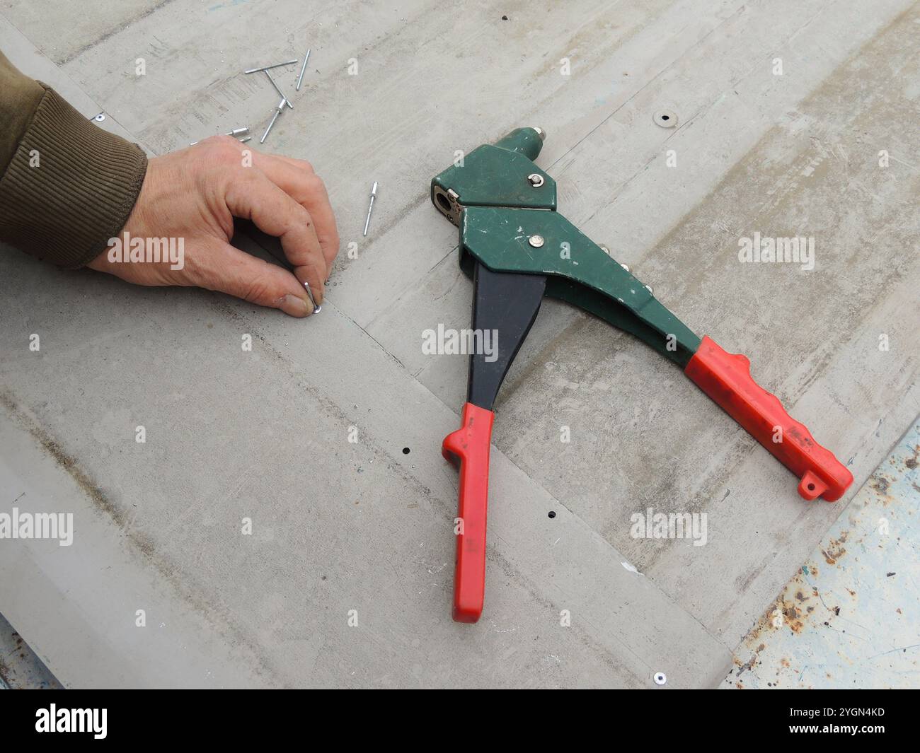 riveting tool on iron texture top view and male hand holding aluminum ...