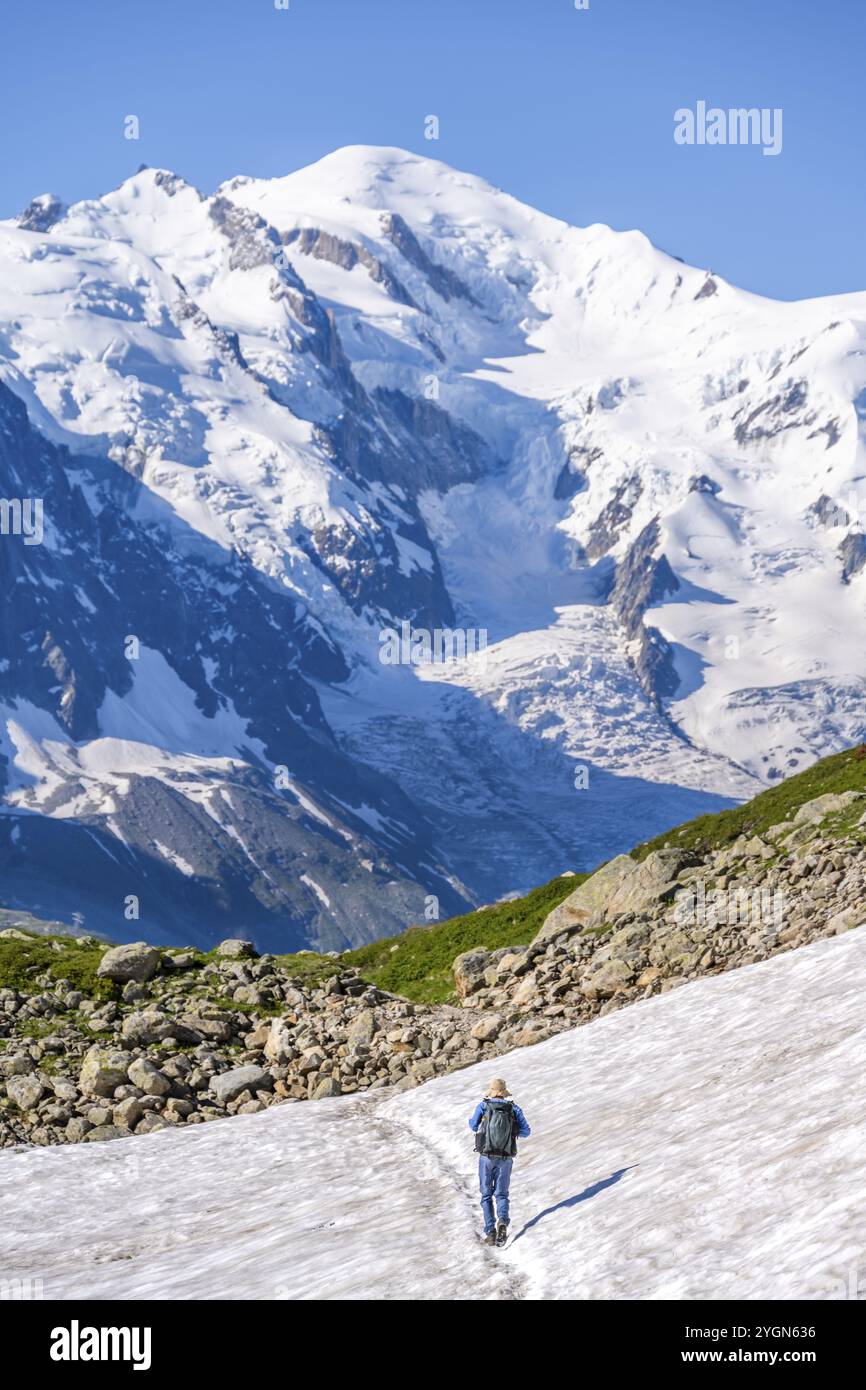 Mountaineer crossing a snowfield, view of spectacular glaciated peaks ...