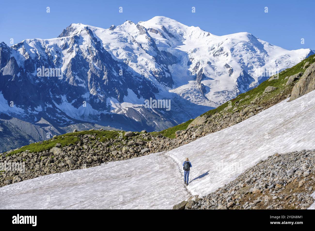Mountaineer crossing a snowfield, view of spectacular glaciated peaks ...