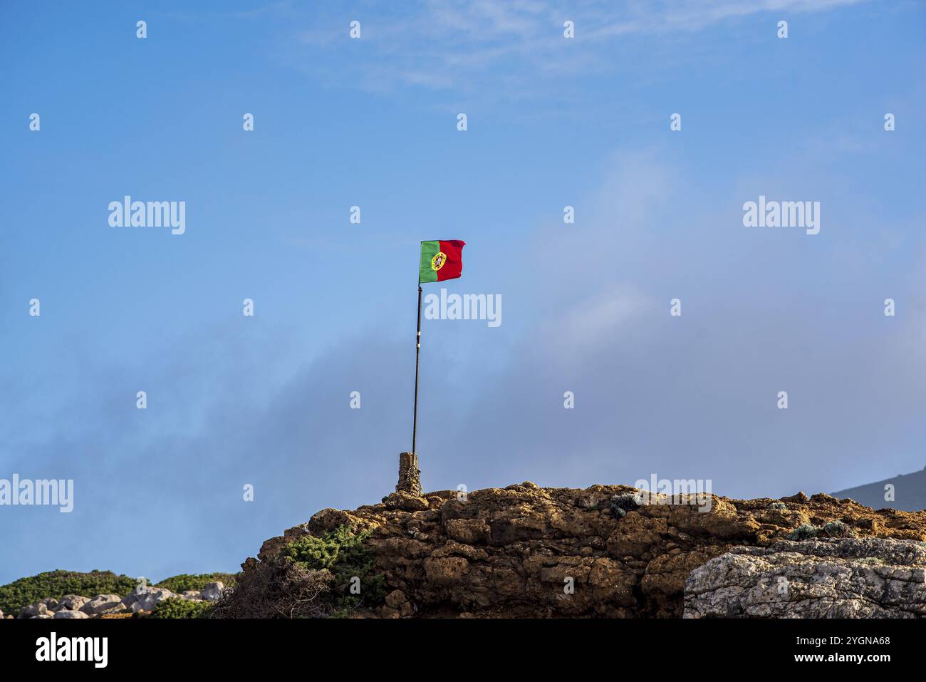 Portuguese flag flying on a rocky hill under a clear blue sky, Portugal ...