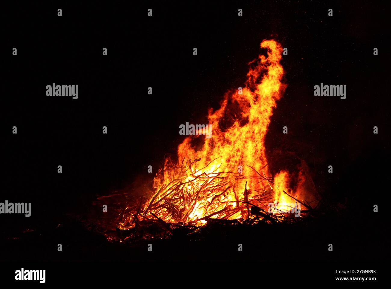 Large bonfire with flames shooting in the air at night. The fire has ...