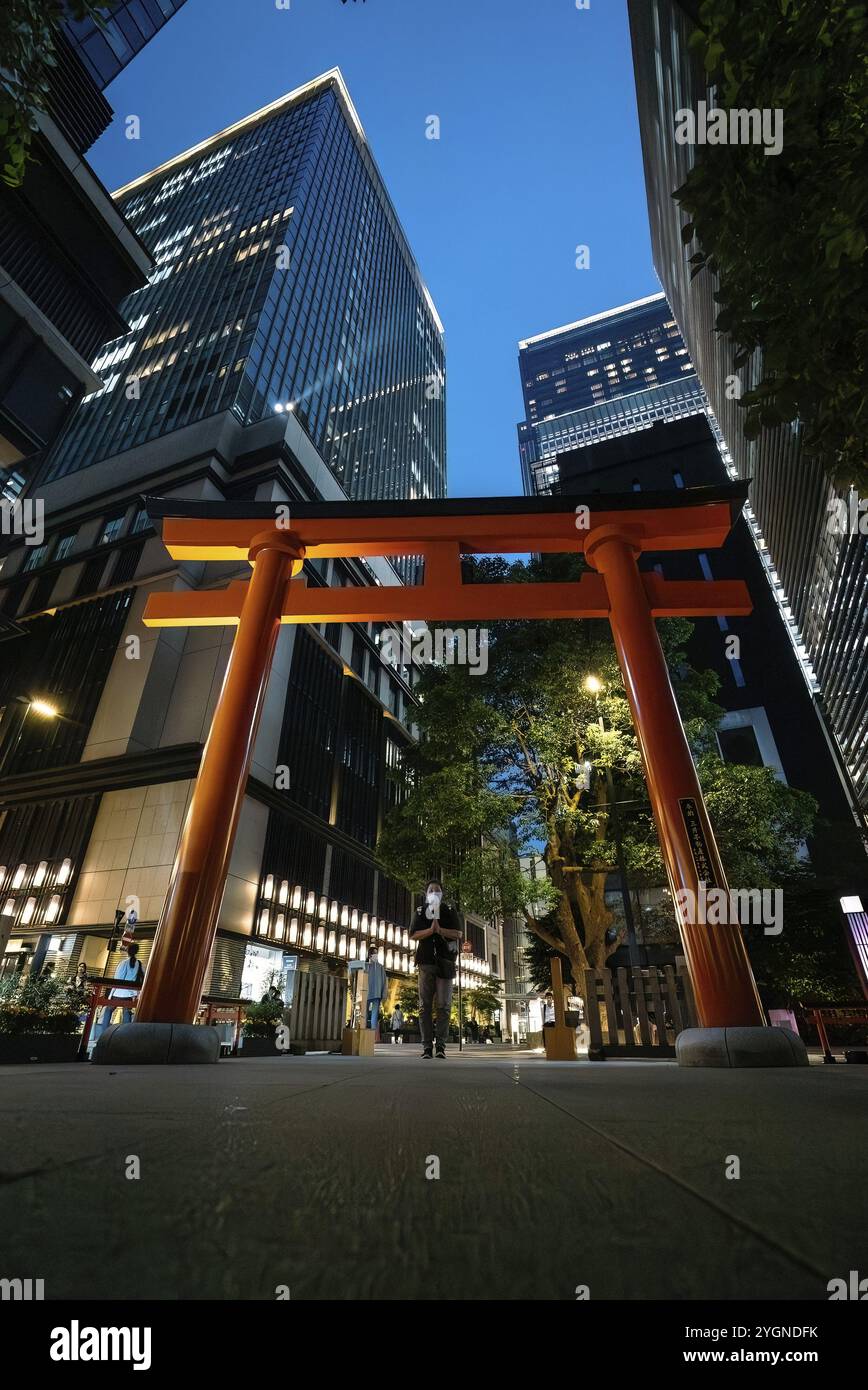 A woman stands in the evening under the Tor tor, which represents the entrance to the shrine ...