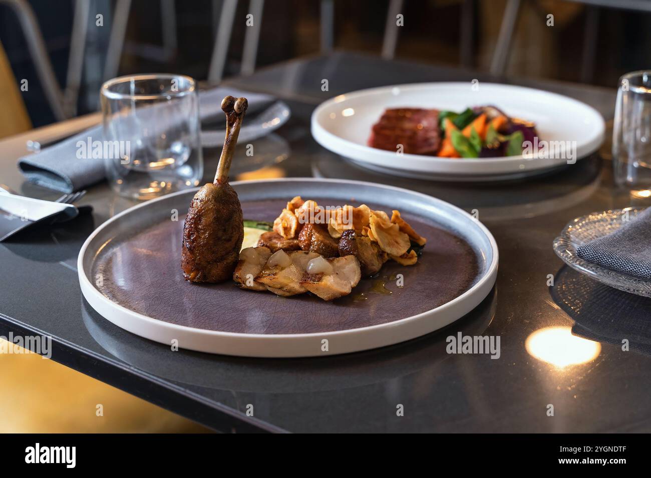 Duck leg confit with roasted mushrooms served on modern ceramic plate ...