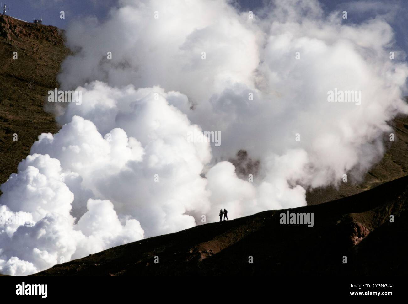 Two people standing in geothermal power plant fog, surrounded by steam ...