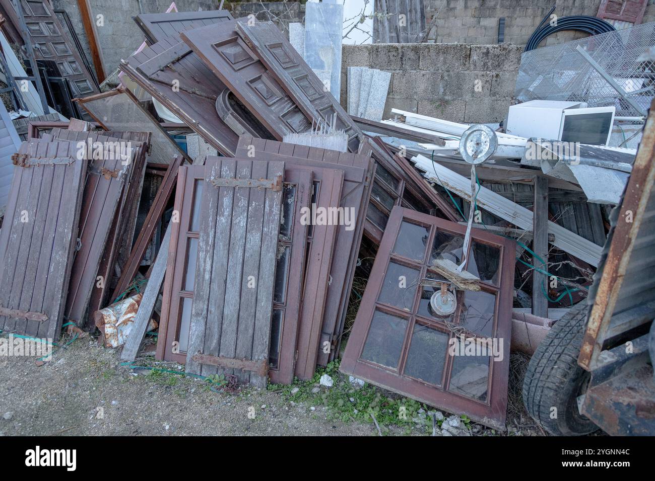 A pile of discarded wooden shutters, doors, and windows with cracked ...