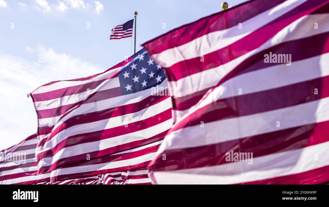 Multiple American flags are waving in the wind against a blue sky with ...