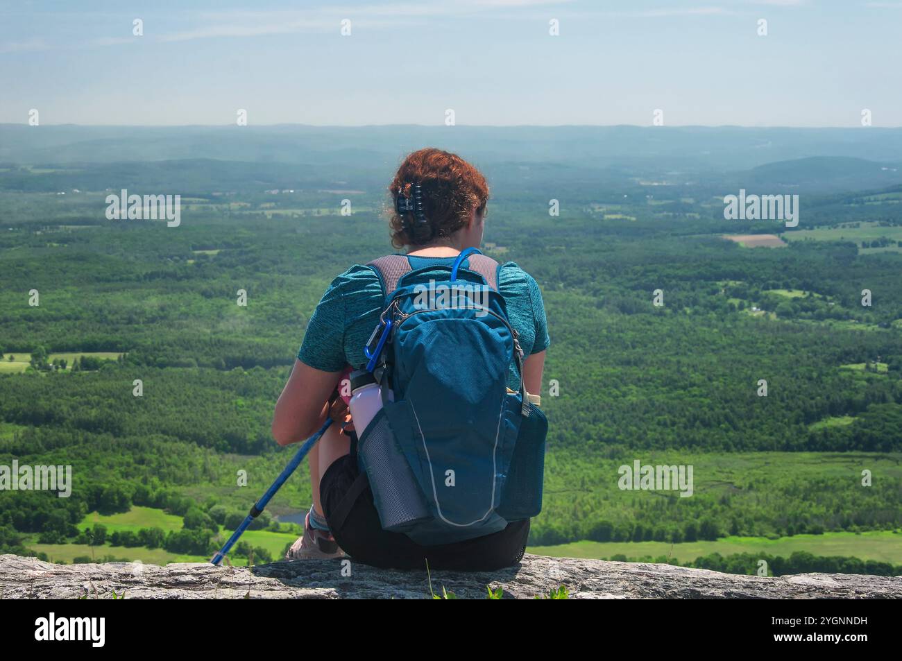 a young female sitting on the edge of a cliff on top of Mount Race on ...