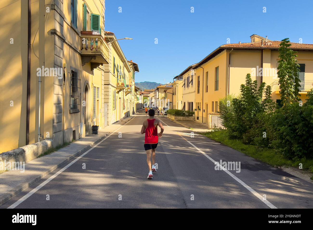 rear view runner running down street of Italian city half marathon race ...