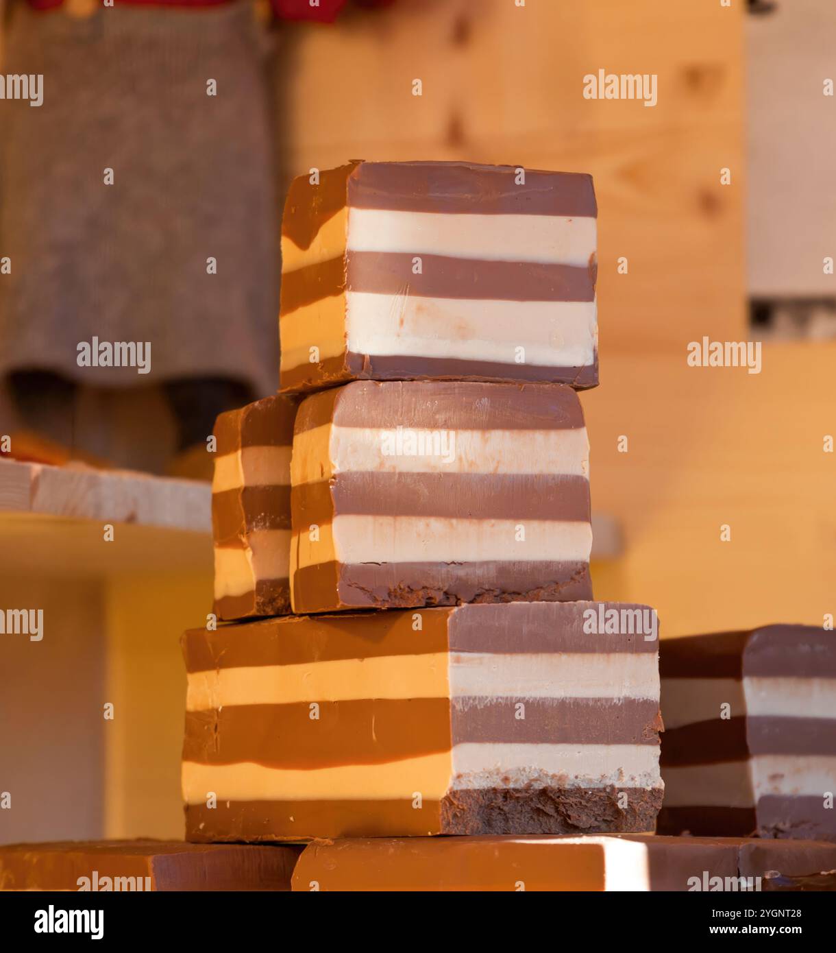 Creamy layered chocolate bars stacked high on display at a market stall ...