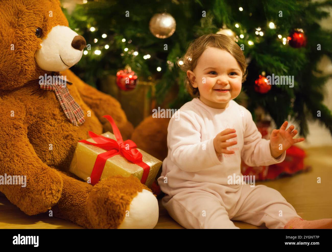 Adorable baby girl clapping hands, sitting next to a giant teddy bear ...