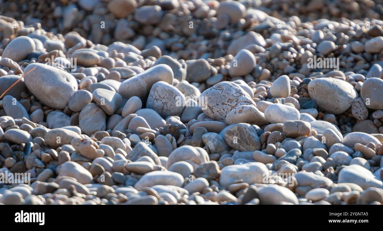 Sun shines on smooth stones creating a natural textured background on a ...