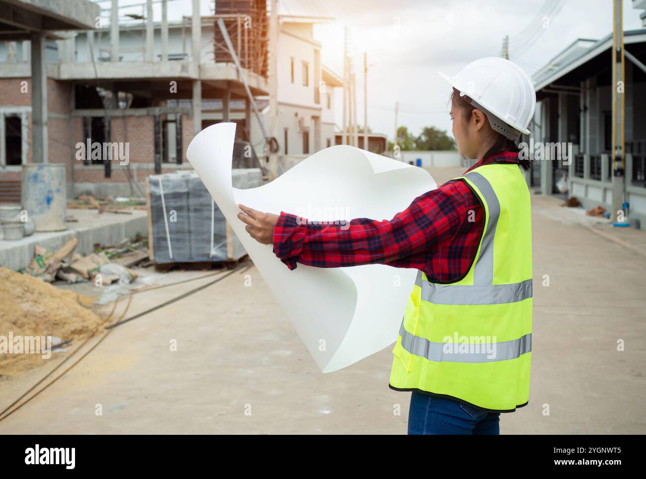Engineers holding blueprint project working outdoors building side with ...