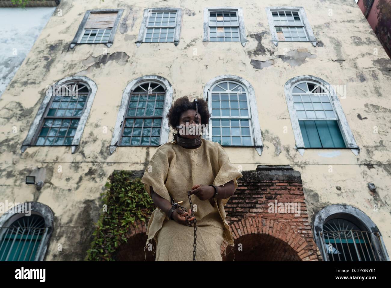 Black woman dressed as a slave, chained and with an iron mask over her ...