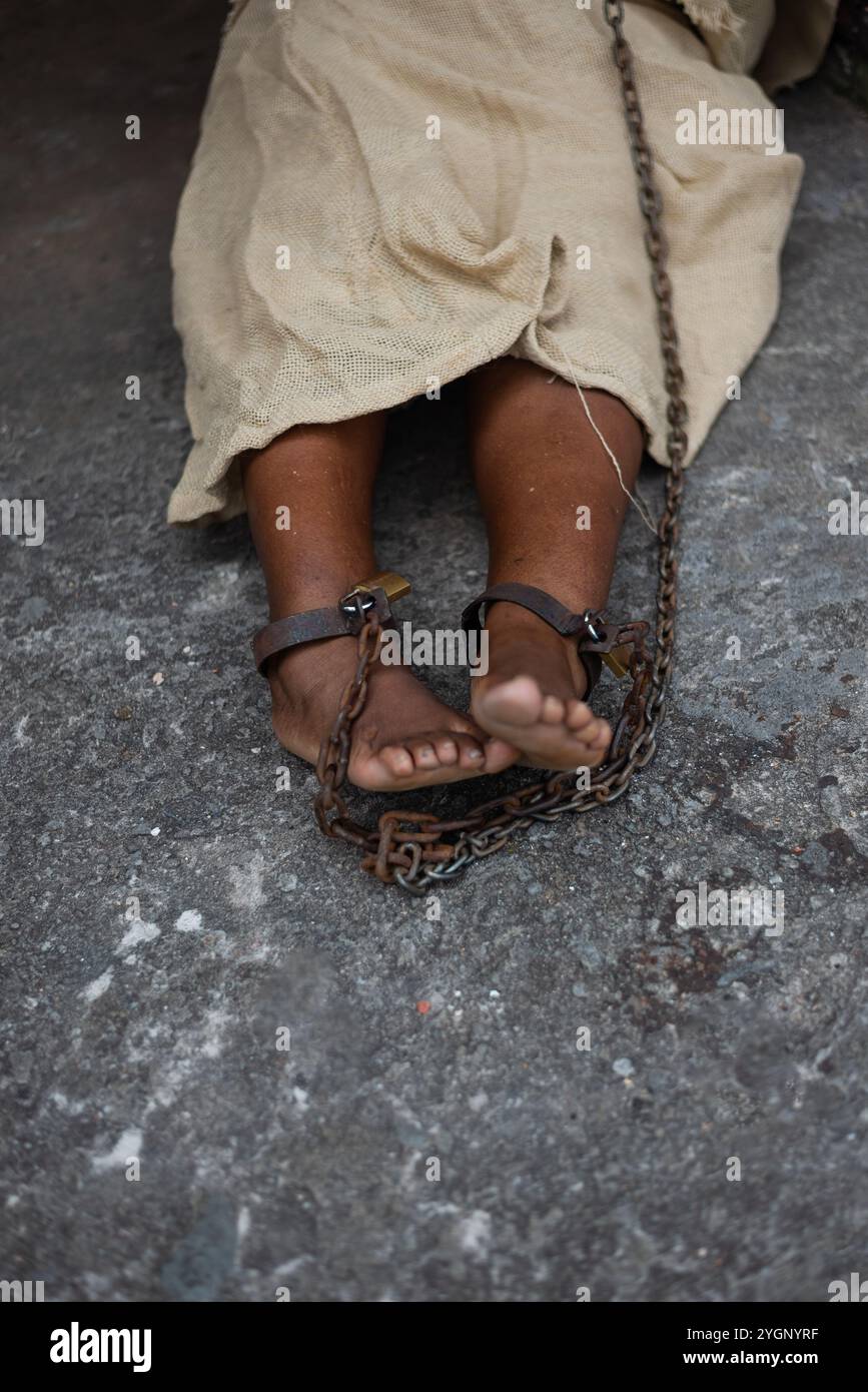 Photo of the chained feet of a black woman sitting on the floor of ...