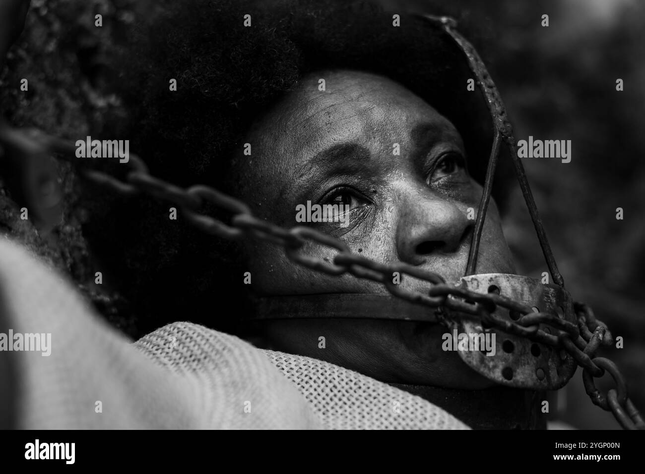 Portrait of a black woman's face with an iron mask stuck in her mouth ...