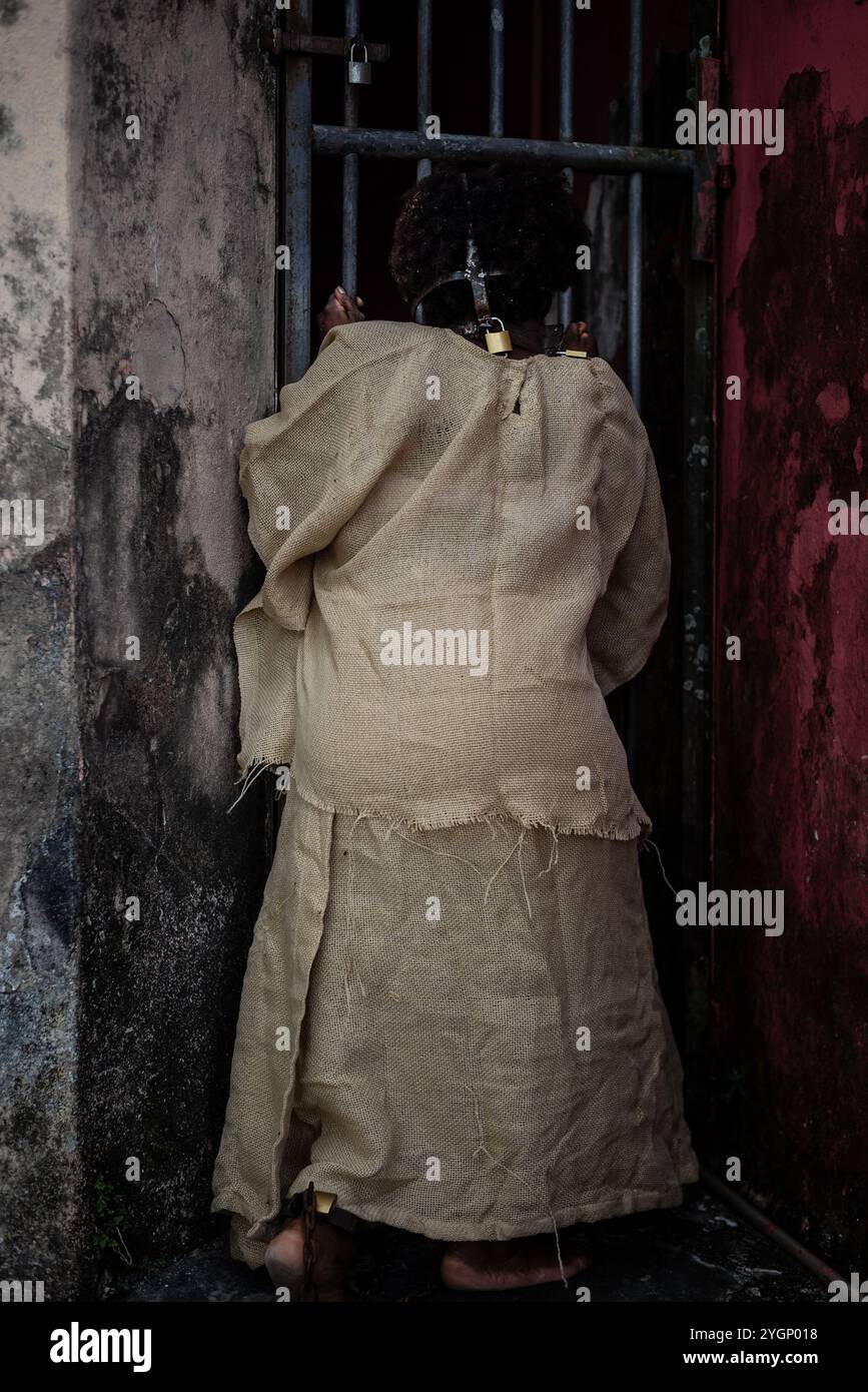 Portrait of a black woman dressed as a slave, chained with an iron mask ...