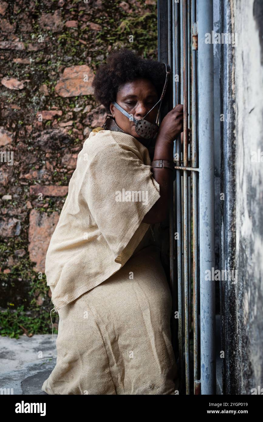 Black woman dressed as a slave, chained with an iron mask on her mouth ...