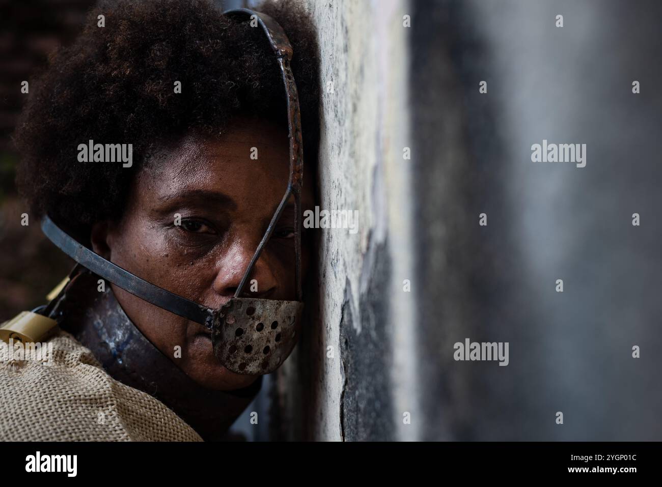 Portrait of a black woman's face with an iron mask stuck in her mouth ...