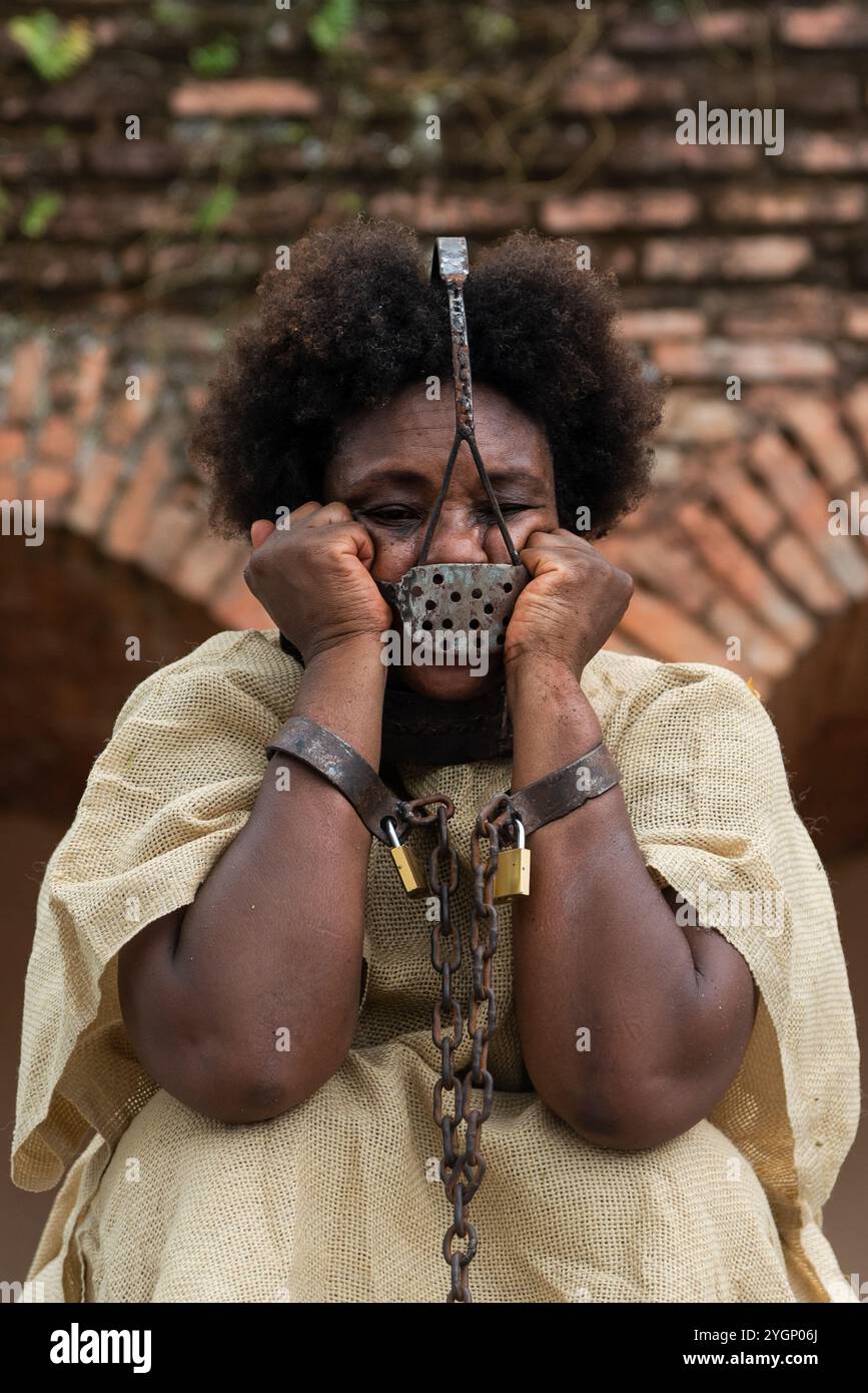 Black woman dressed as a slave, chained and with an iron mask on her ...