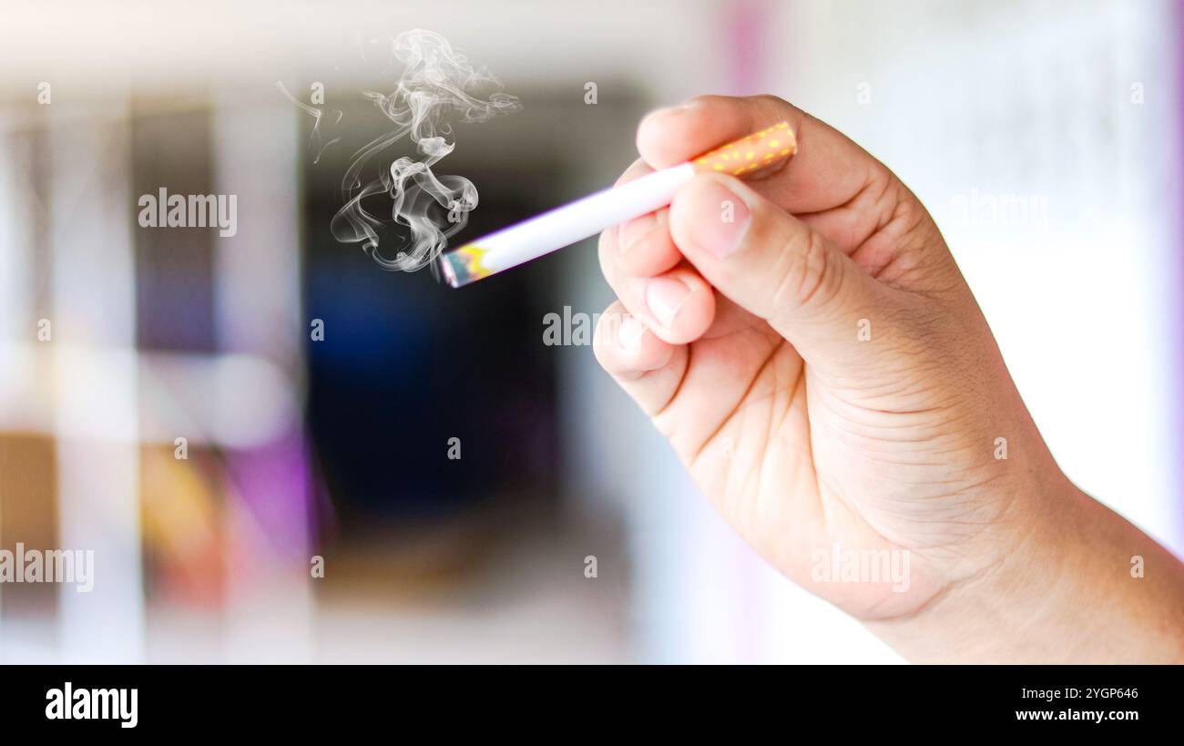 A hand holding a cigarette with smoke drifting upward, representing an ...