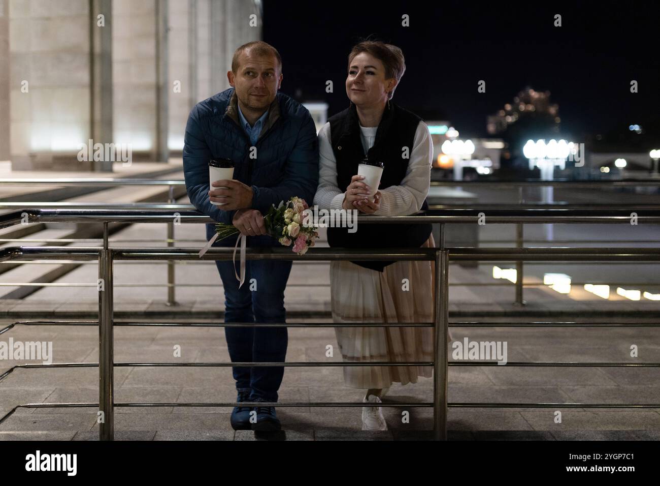 A couple strolls through the city at night, enjoying a quiet moment ...