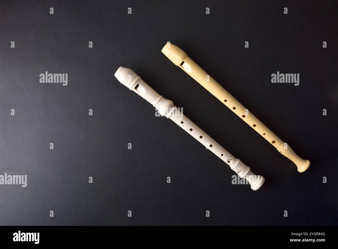 Detail of two different plastic recorders in shape and color on a black ...