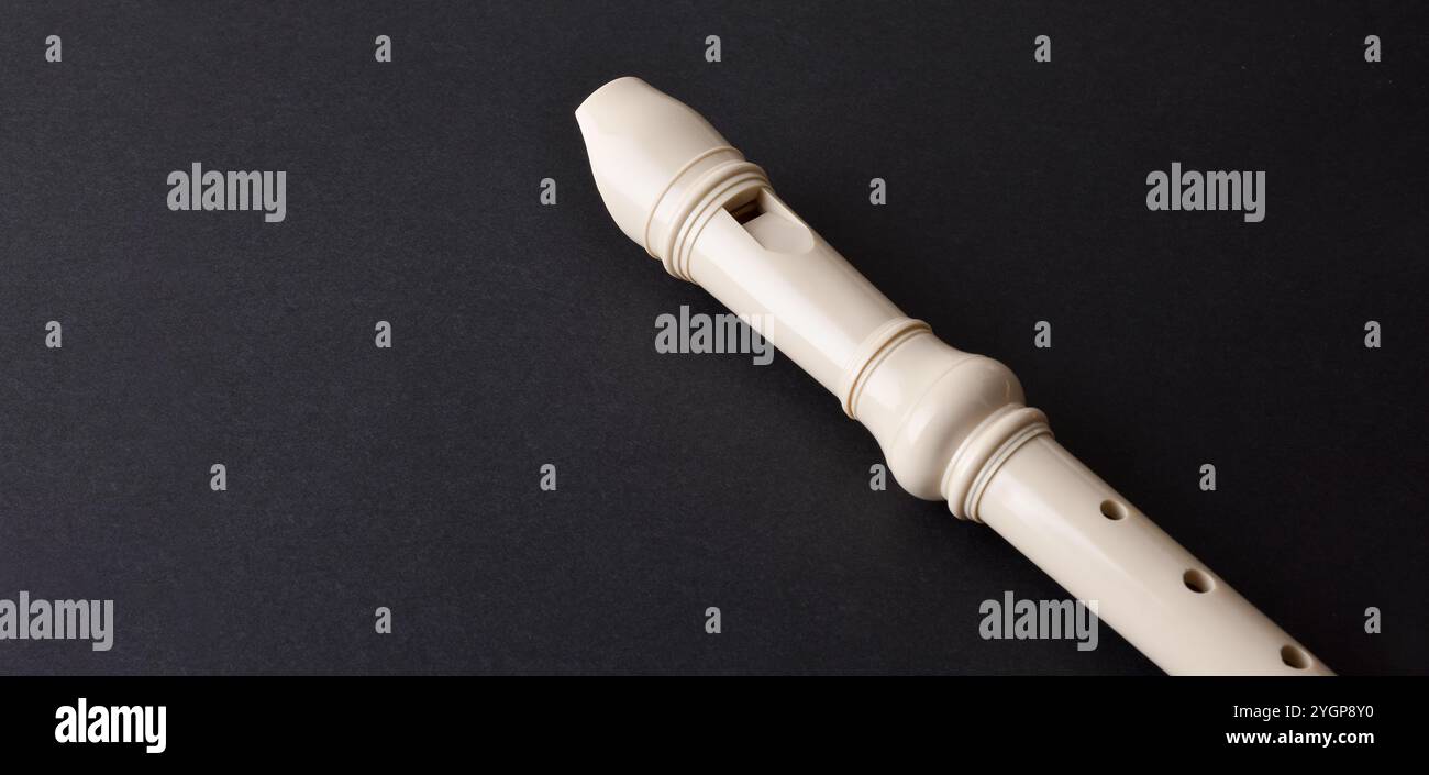 Musical background with detail of white plastic recorder on black ...