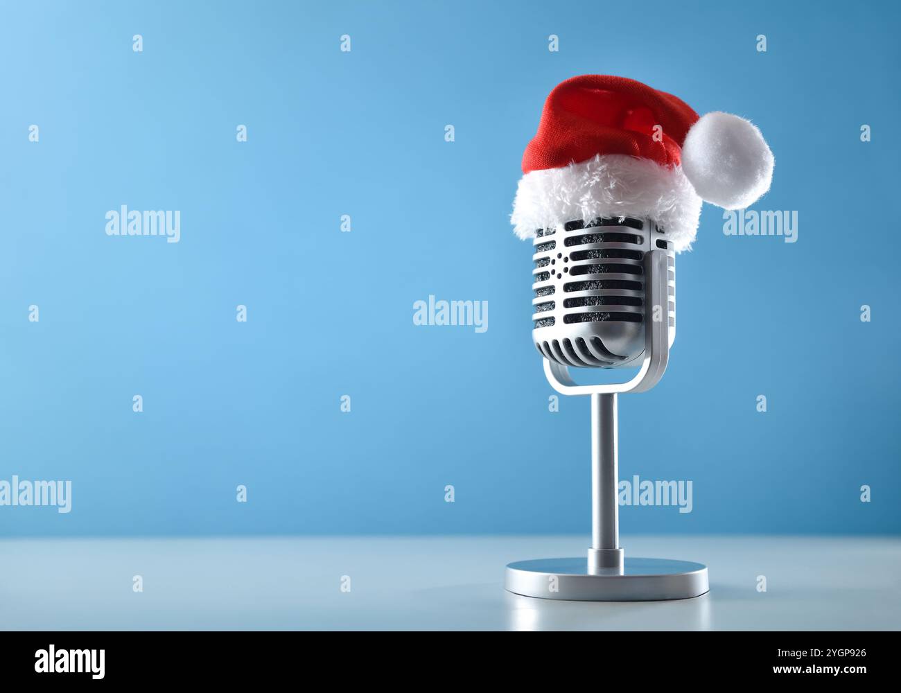 Retro metal microphone with stand and Santa hat on top on white table ...