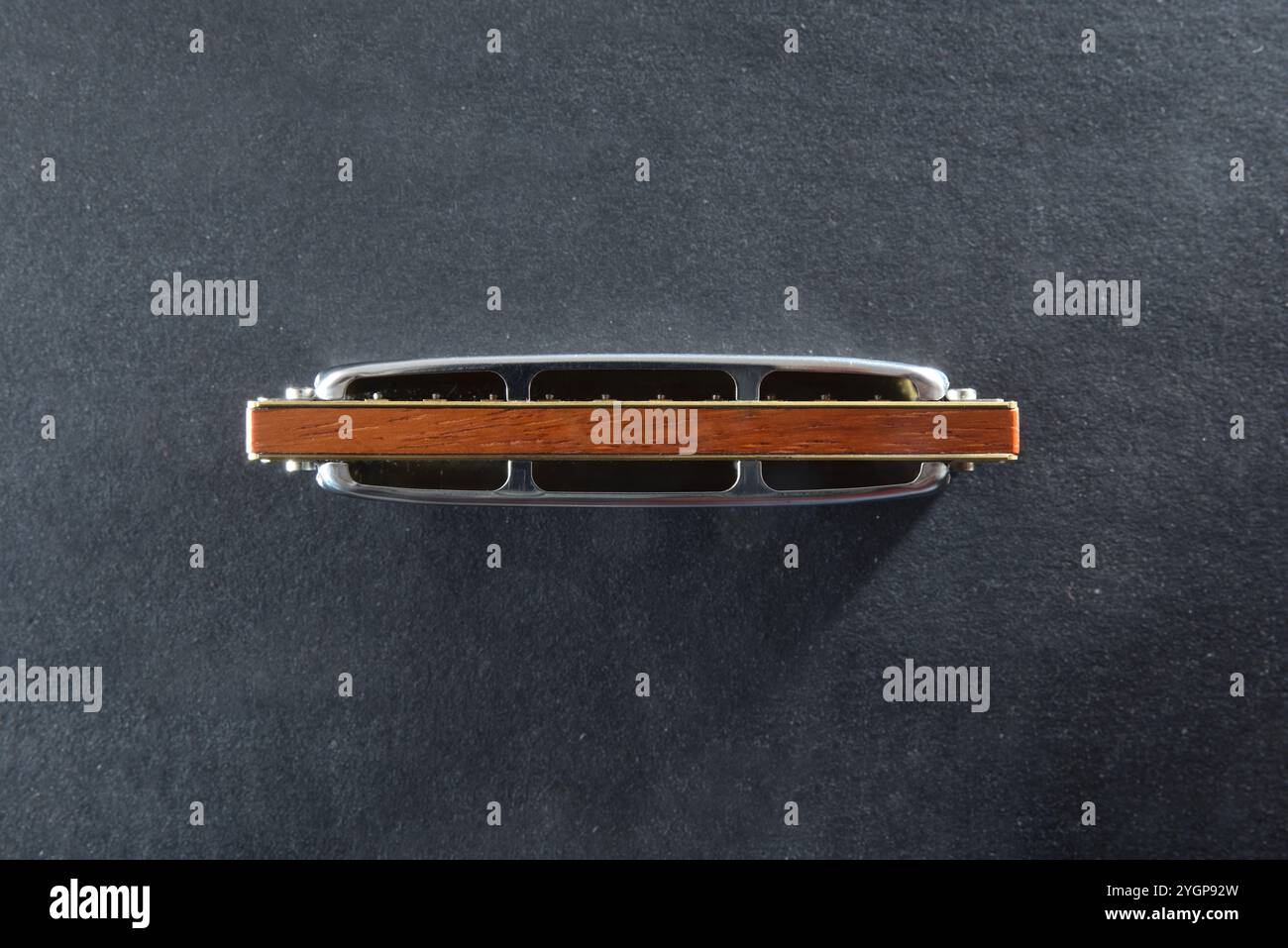 Back of metal and wood diatonic harmonica isolated on textured black ...