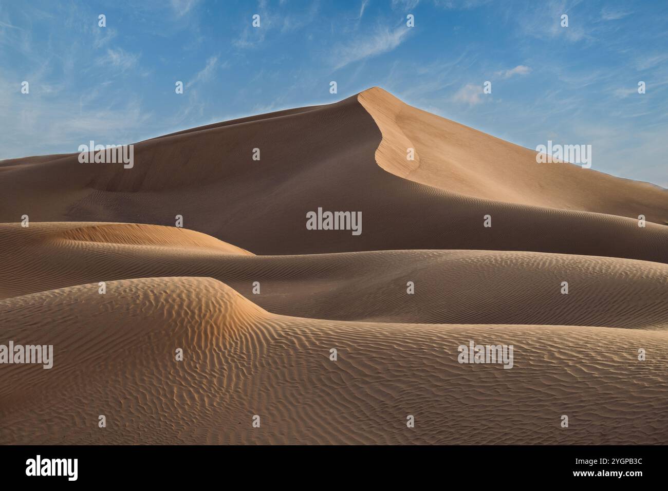 Golden sand dune in Le Khwair, Oman, surrounded by smooth, rippling ...