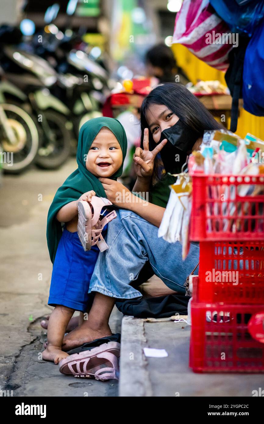 A young Muslim Filipino girl is dressed by her mother in the clothing ...