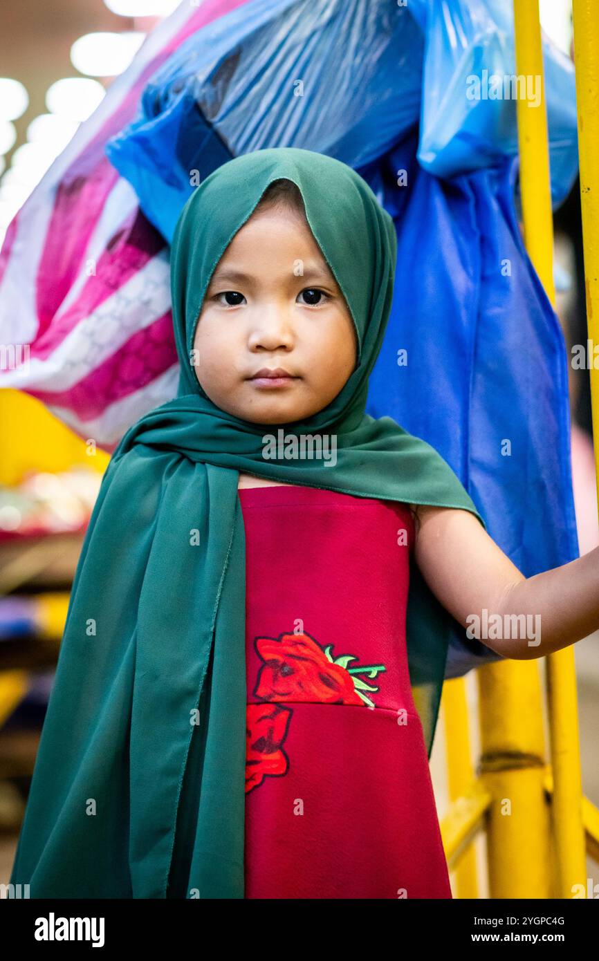 A young Muslim Filipino girl is dressed by her mother in the clothing ...