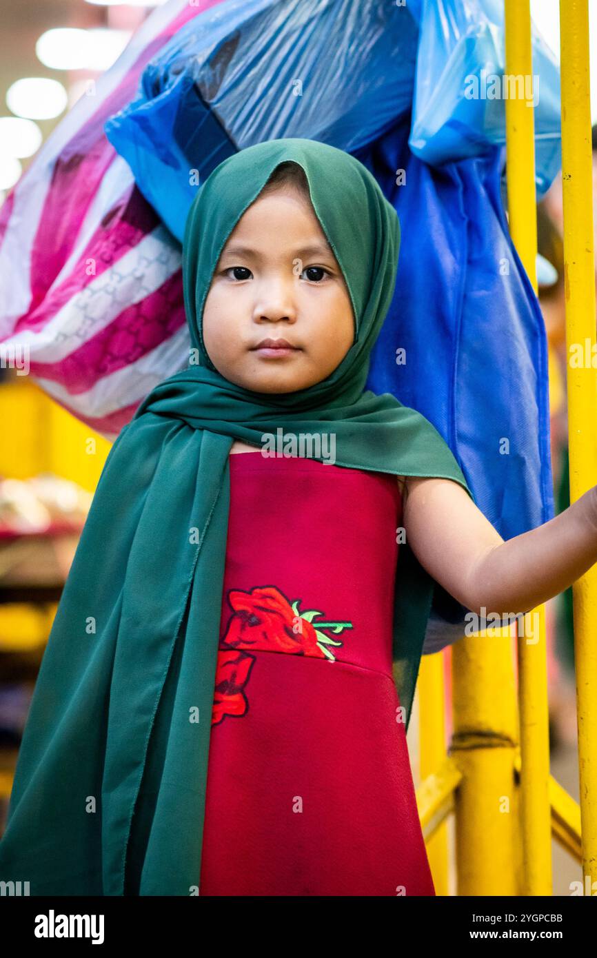 A young Muslim Filipino girl is dressed by her mother in the clothing ...