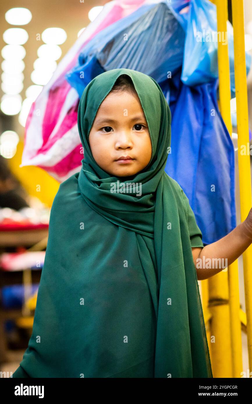 A young Muslim Filipino girl is dressed by her mother in the clothing ...