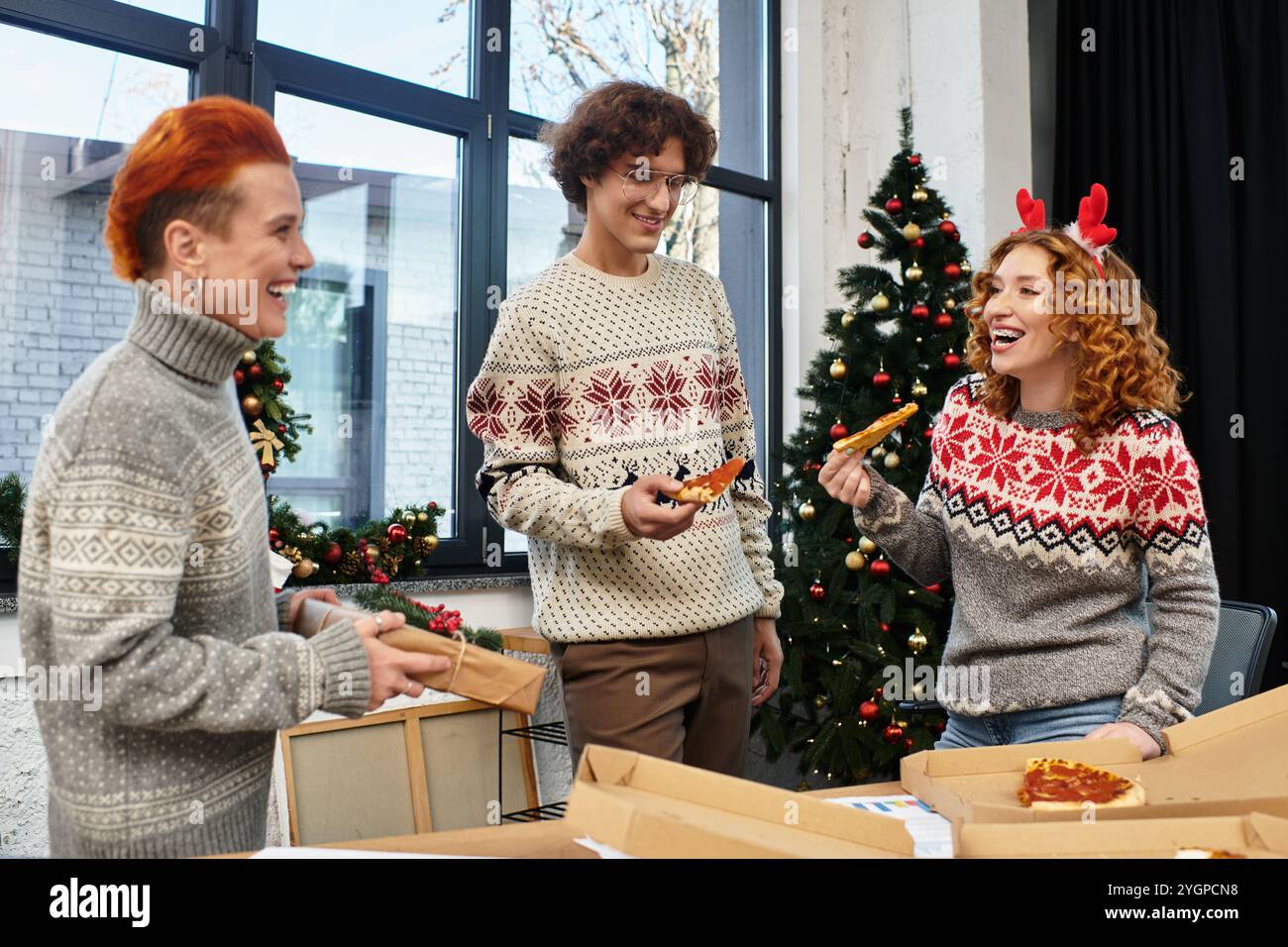 Colleagues share pizza and laughter while enjoying a cheerful Christmas ...
